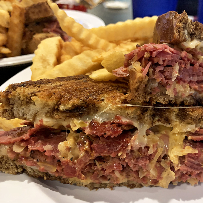 The money shot—where melted Swiss cascades over perfectly pink corned beef, creating the kind of sandwich that ruins all other lunches for you.