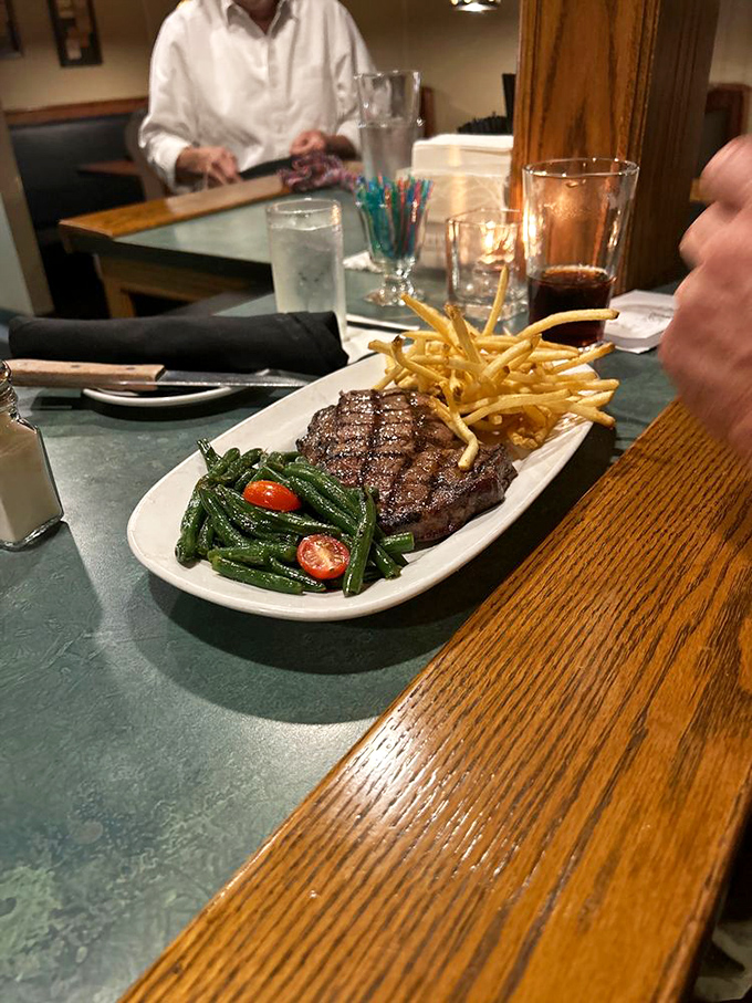 A perfectly seared steak flanked by crispy fries and vibrant green beans – the holy trinity of steakhouse satisfaction.