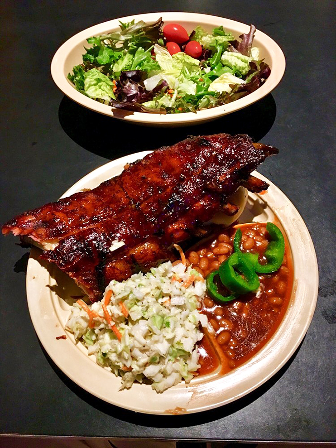 A rack of ribs shares the spotlight with fresh coleslaw and beans, while jalapeños add a touch of green to this symphony of smoke.