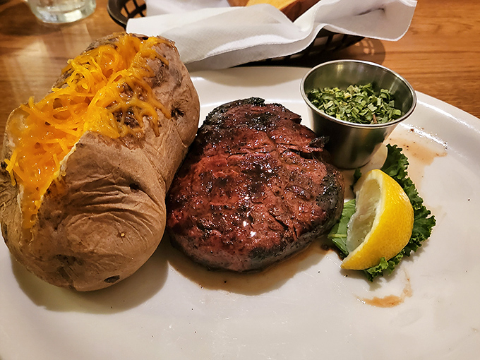 That loaded baked potato could be a meal itself, but it knows its place—loyal sidekick to the smoky, flame-kissed filet that's the undisputed star of this plate.