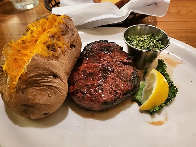 That loaded baked potato could be a meal itself, but it knows its place—loyal sidekick to the smoky, flame-kissed filet that's the undisputed star of this plate.