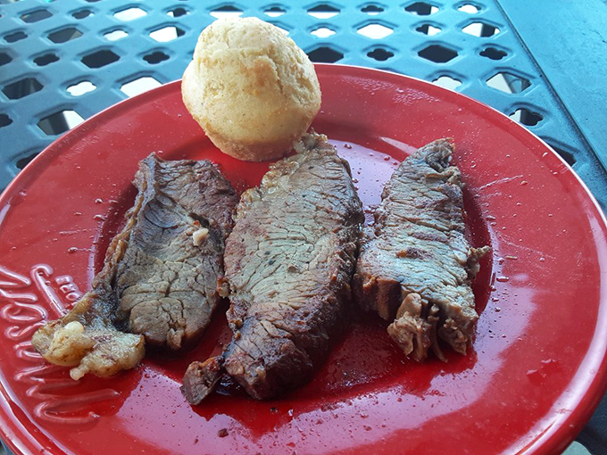 Three slices of brisket and a cornbread muffin on a red plate—a simple presentation that lets the star of the show take center stage without unnecessary distractions.
