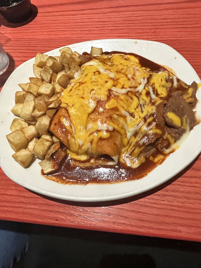 Behold the holy trinity of Southwestern cuisine: crispy home fries, cheese-blanketed enchiladas, and that rich red chile sauce that would make even your most stoic friend weep with joy.
