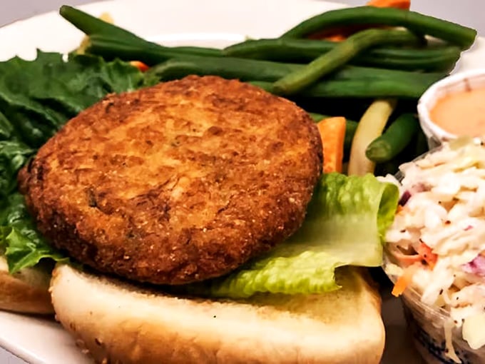 The crab cake sandwich—where seafood dreams meet bread reality. Served with fresh vegetables and coleslaw that doesn't feel like an afterthought.