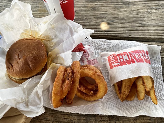 The holy trinity of comfort: a perfectly simple burger, crispy onion rings, and hand-cut fries—lunch doesn't get more straightforward or satisfying.
