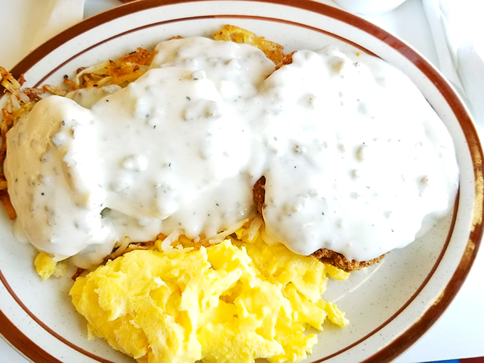 Comfort on a plate—hash browns crisped to perfection, smothered in creamy gravy, with sunny eggs standing by for moral support.