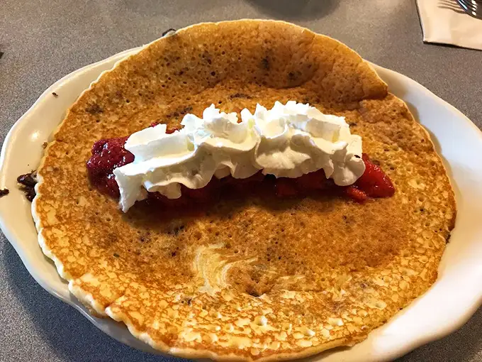 This pancake isn't just large—it's the size of your childhood dreams. The whipped cream and strawberry filling make it breakfast's answer to dessert.