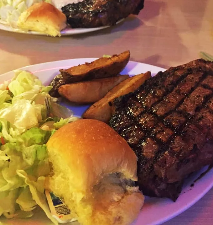 The grill marks tell stories of flame-kissed perfection, while that potato stands guard like a delicious sentinel of heartland dining.