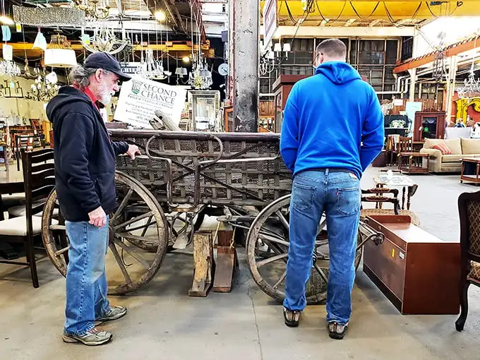 Treasure hunters examining what appears to be a horse-drawn cart, proving that "impulse buy" has a whole different meaning at Second Chance.