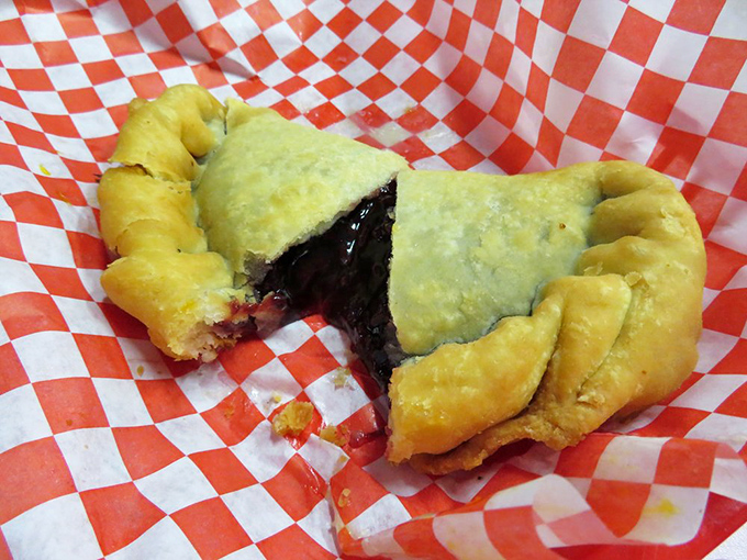 The moment of truth—a blackberry fried pie torn open reveals its purple treasure, like nature's jam packed into a portable pastry pocket.