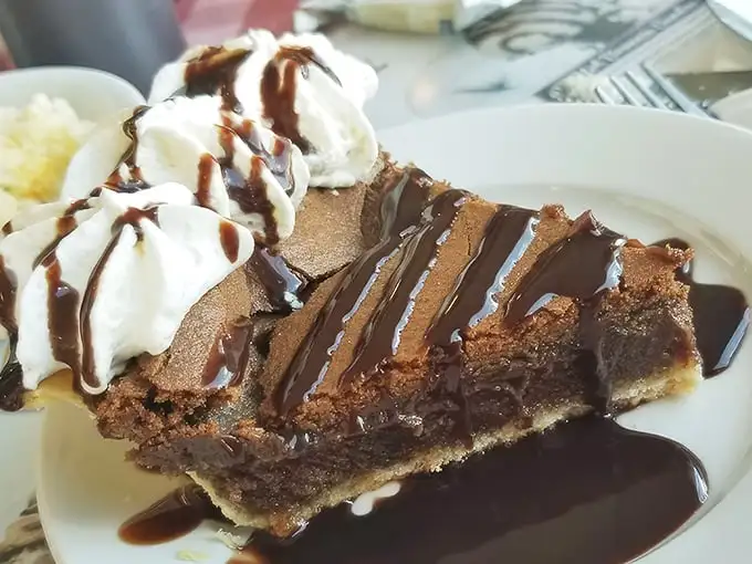 Chocolate chess pie drizzled with sauce and topped with whipped cream—because sometimes dessert should look like it's dressed for the prom.