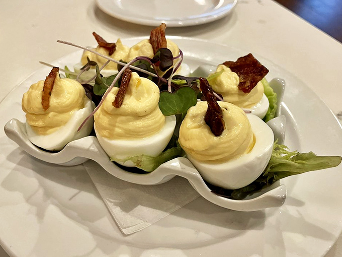 The deviled egg – reimagined. Creamy filling piped with precision, crowned with crispy bacon and delicate greens. Simplicity and decadence on one plate.