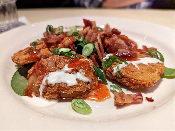 Fried green tomatoes: the South's gift to civilization. Crispy, tangy discs topped with creamy sauce and bacon—vegetables that make you forget they're good for you.