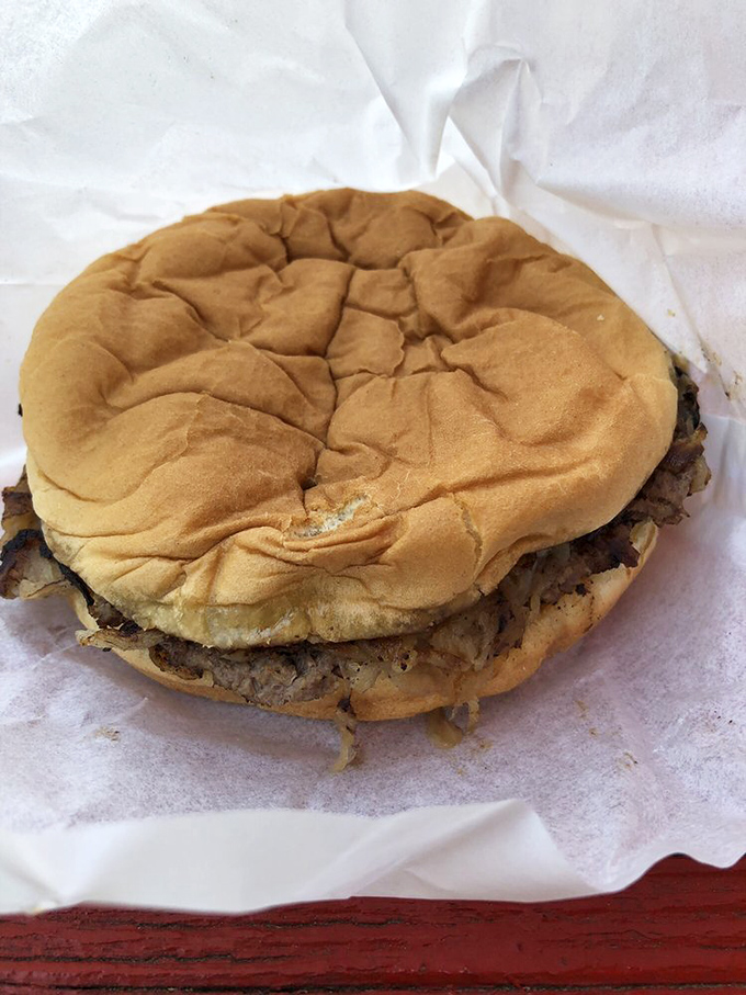 The humble onion burger in its natural habitat—wrapped in paper, ready to be devoured, with those crispy onion edges that burger dreams are made of.