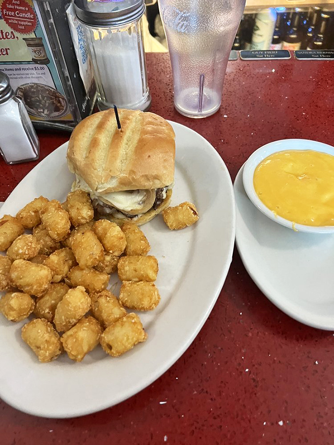 This isn't just a burger—it's architecture. The tater tots standing guard nearby know they're in the presence of greatness.