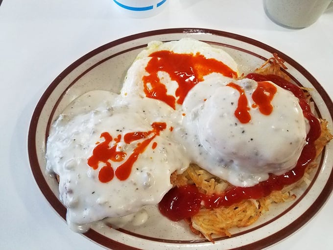 Breakfast paradise found: crispy hash browns crowned with sausage gravy and a splash of ketchup—proof that morning meals don't need to be complicated to be magnificent.
