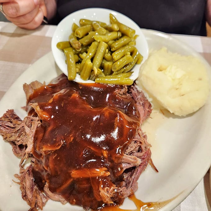 Tender roast beef swimming in rich gravy alongside green beans and mashed potatoes—comfort food that speaks a universal language.