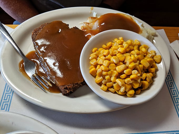 A slice of meatloaf swimming in rich brown gravy alongside sweet corn – proof that midwestern cuisine isn't fancy, but it knows how to hug your soul.