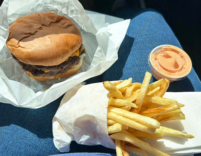 The classic combo—a perfectly proportioned burger alongside golden fries with a side of fry sauce that deserves its own fan club.