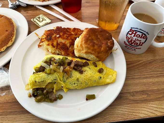 The breakfast plate that launched a thousand road trips – an omelet stuffed with possibility, hash browns crisp at the edges, and a biscuit begging for butter.