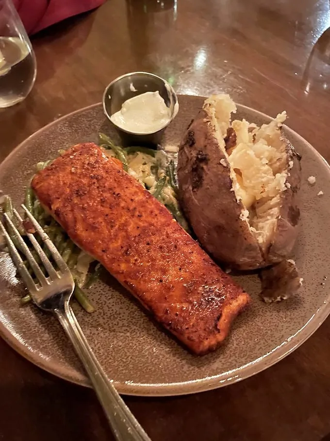 Salmon that's dressed better than most people at a wedding, resting on a bed of asparagus with a baked potato standing guard.