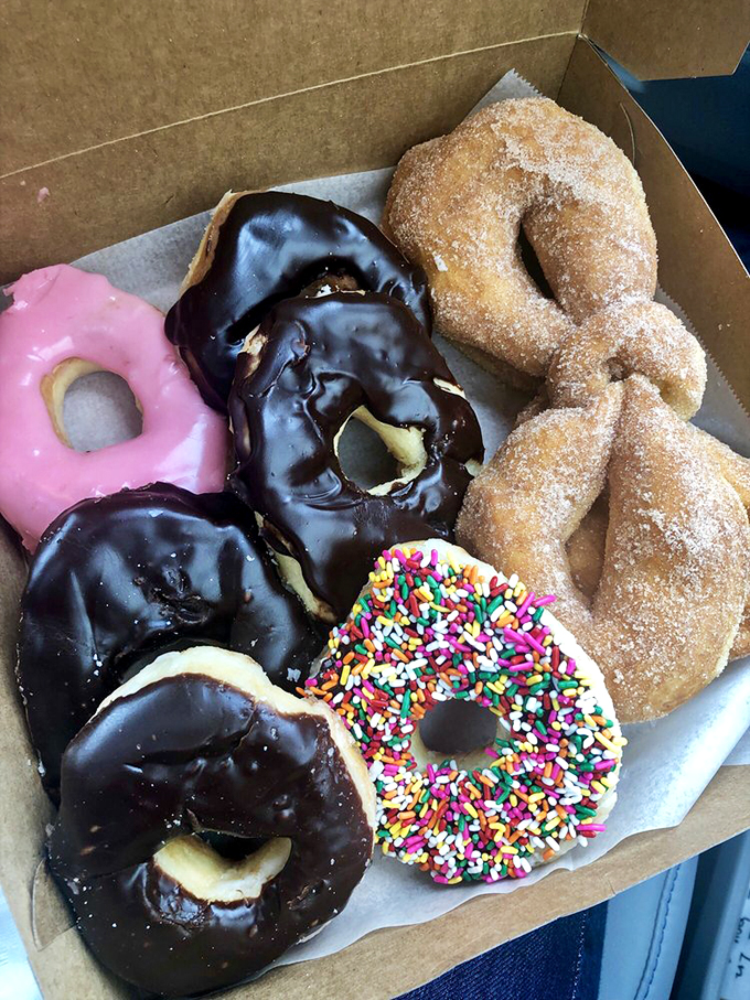A dozen glazed donuts nestled in their cardboard sanctuary. Some people see breakfast; I see an afternoon of zero regrets.