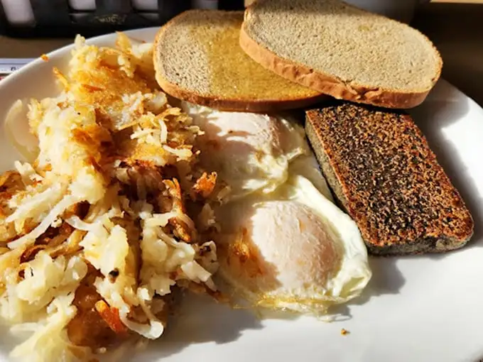 A breakfast trinity that would make any morning person weep with joy—crispy hash browns, perfectly cooked eggs, and toast ready for butter baptism.