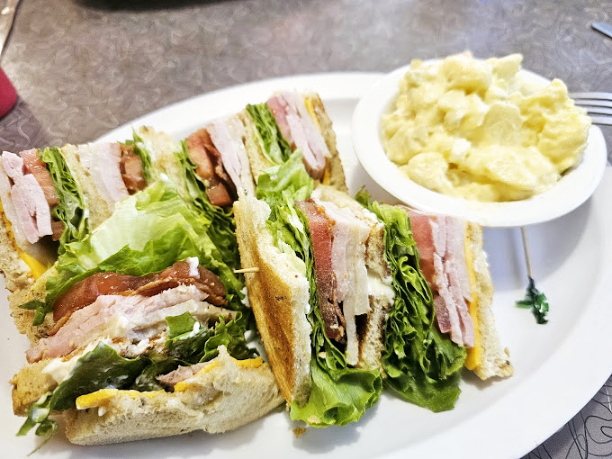 The club sandwich – architecture you can eat! Layers of fresh ingredients stacked between toasted bread with a side of potato salad that didn't come from any factory.