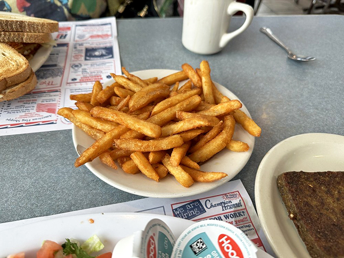 Golden French fries piled high like tiny log cabins of potato perfection—simple pleasures that remind you why diners endure while trends fade.