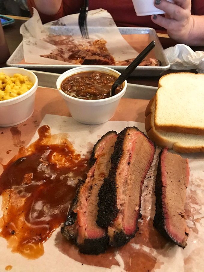 Brisket bathing in sauce with mac and cheese standing by. This tray represents what happiness looks like in solid form—no filter needed.
