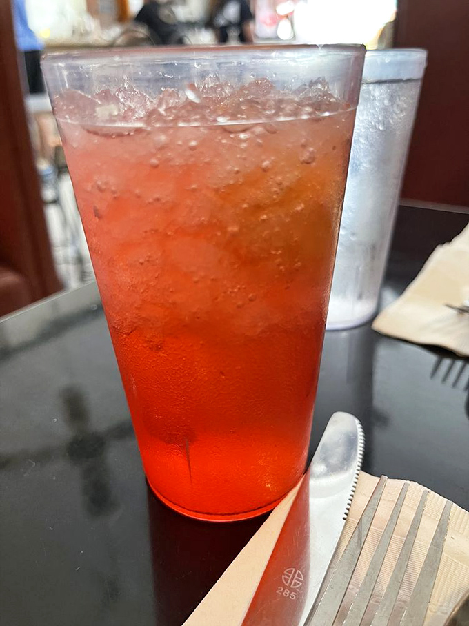 That vibrant red drink isn't just refreshing—it's like summer decided to throw a party in a glass, complete with ice cubes that tinkle like wind chimes.