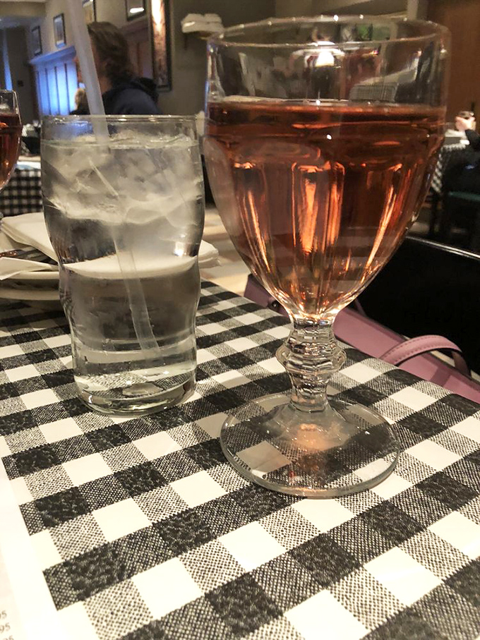 A glass of rosé and water on classic checkered tablecloths. Sometimes the perfect dining companion isn't conversation—it's a good glass of wine.