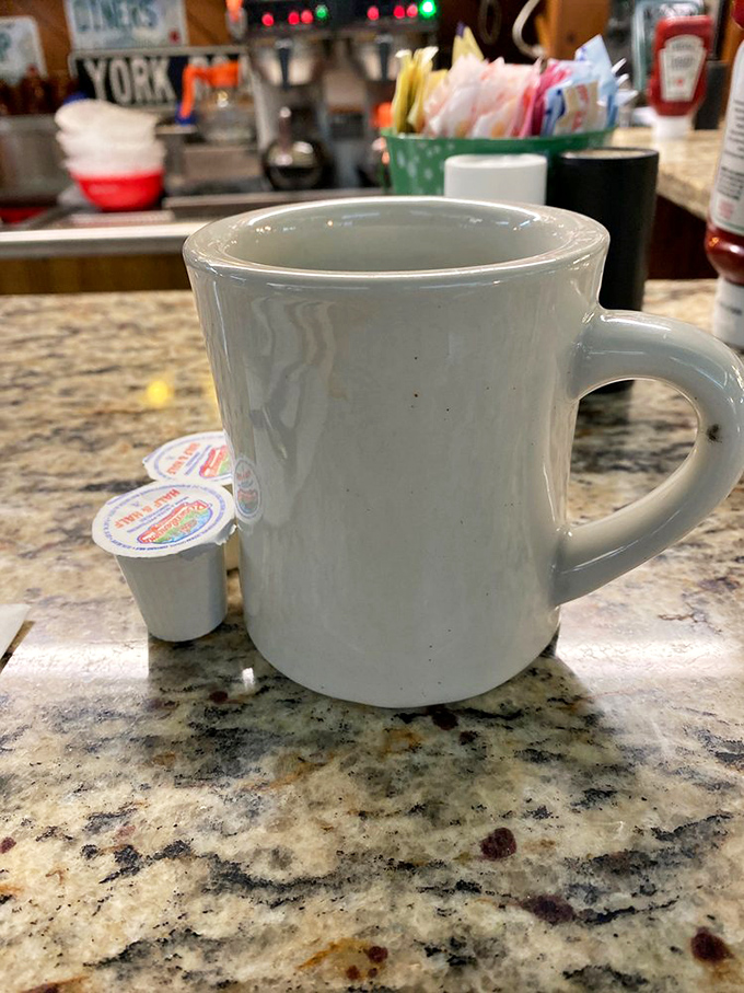 The sturdy white mug—diner code for "we're serious about coffee." No fancy latte art, just honest brew that keeps coming until you surrender.