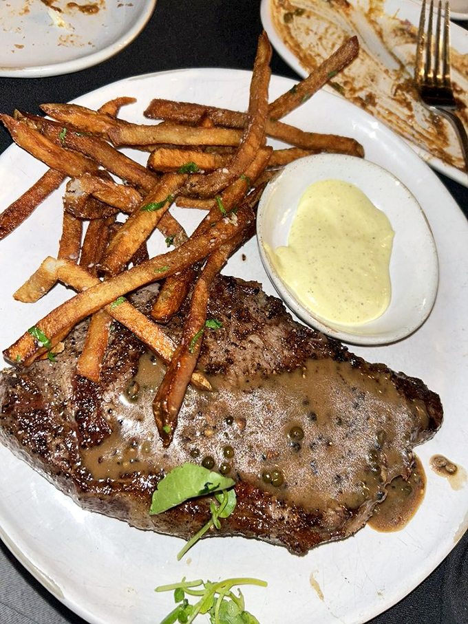 A ribeye swimming in peppercorn sauce alongside fries that have been to finishing school. This plate has more class than a Yale reunion.