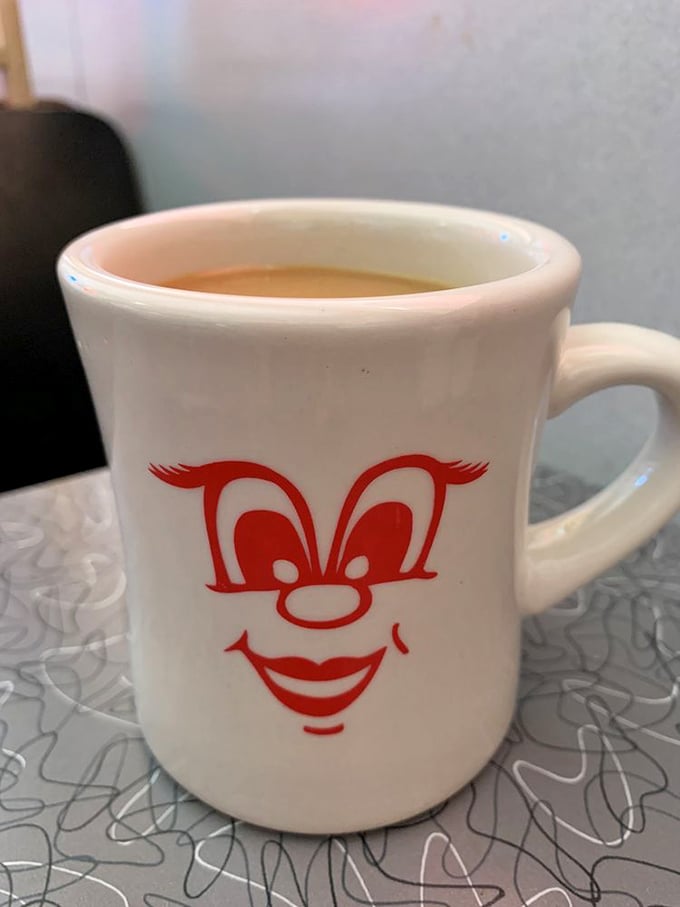 The coffee mug grins because it knows what you need before you do. In diners, coffee isn't just a beverage—it's emotional support.