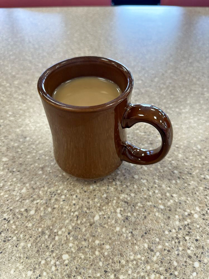 That sturdy brown mug isn't just holding coffee; it's cradling liquid motivation in a vessel that's survived more mornings than most Vegas marriages.