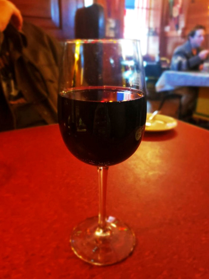 A glass of robust red wine catches the tavern's warm glow—the perfect companion for the parade of proteins about to grace your table.