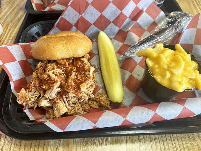 Pulled chicken sandwich with mac and cheese and a pickle spear—proof that barbecue excellence extends beyond the usual pork and beef suspects.