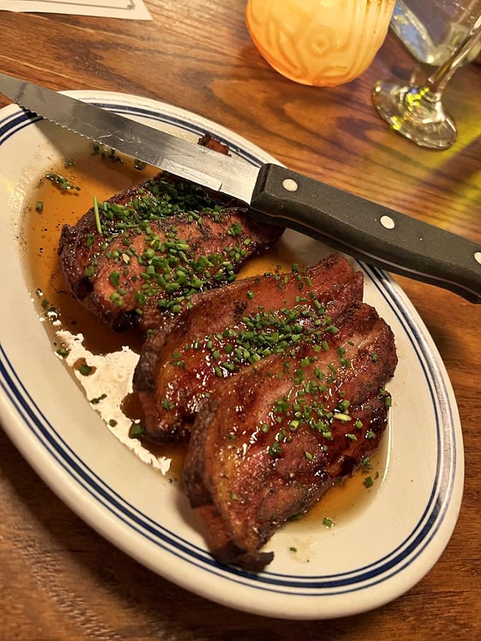Slab bacon that's been transformed from breakfast sidekick to main character. The glistening chive garnish isn't just pretty—it's necessary balance.