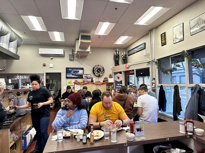 The morning congregation at Fuller's—where strangers become temporary neighbors over coffee that never stops flowing.