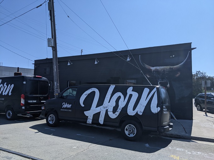 The unassuming exterior of Horn BBQ in Oakland – where that bold white lettering against dark panels is the architectural equivalent of a whisper about the best-kept secret in town.