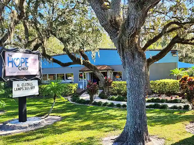 The HOPE Chest welcomes bargain hunters under Florida's majestic oak trees, where the blue building promises treasures within like a retail oasis.