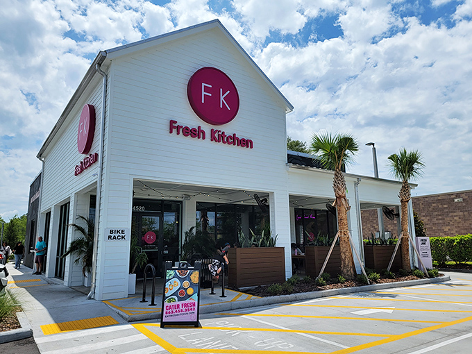 Fresh Kitchen's crisp white exterior with that eye-catching magenta logo stands out like a culinary beacon among Lakeland's palm trees.