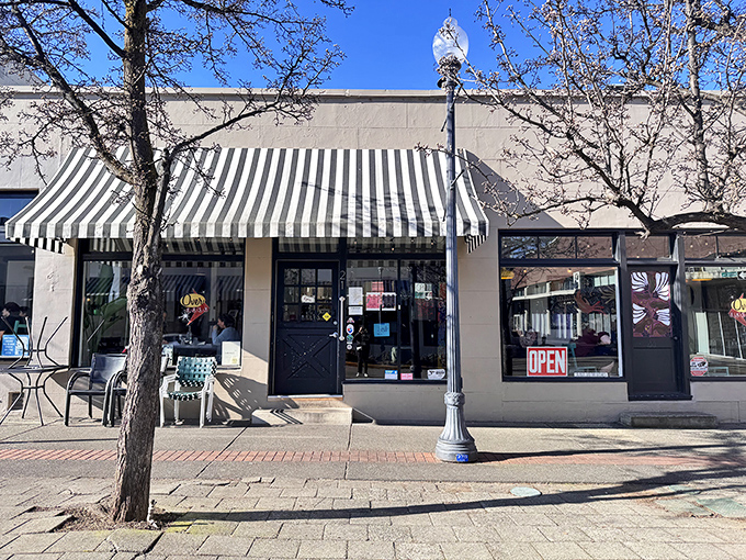 The storefront beckons with its simple charm—black door, striped awning, and outdoor seating that whispers, "Come in, the eggs are waiting." 
