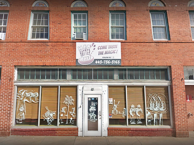 The brick facade of Mad Hatter Cafe beckons with whimsical window art and a turquoise awning—Lewis Carroll's fantasy brought to life on Salisbury's Main Street.
