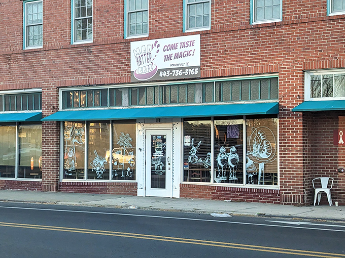 The brick facade of Mad Hatter Cafe beckons with whimsical window art and a turquoise awning—Lewis Carroll's fantasy brought to life on Salisbury's Main Street.