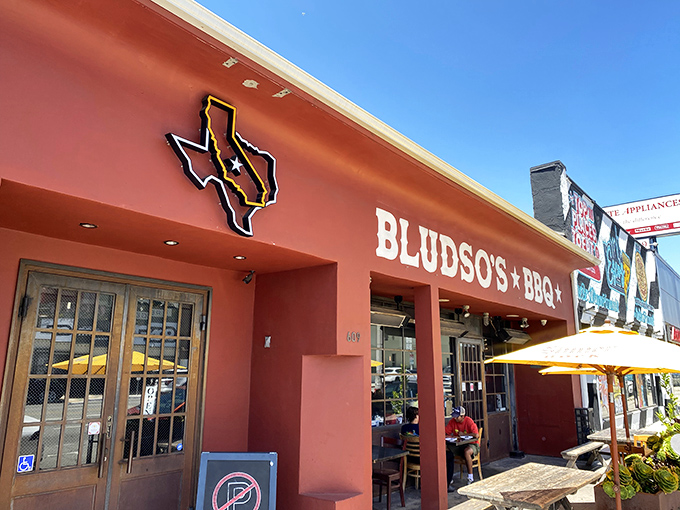 The crimson facade of Bludso's stands like a temple to Texas tradition, complete with succulent planters that say, "Slow down, you're about to enter sacred smoke territory."
