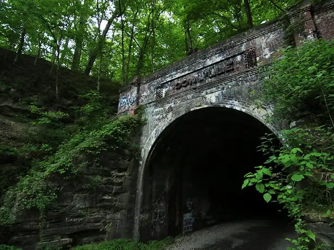 Nature reclaims what man abandoned at Moonville Tunnel, where vibrant greenery frames this portal to the past. The perfect backdrop for both daytime adventures and nighttime frights.