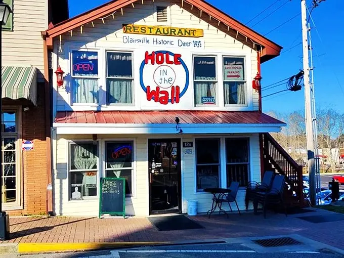 The iconic facade of Hole in the Wall beckons hungry travelers with its charming hand-painted sign and string lights—a North Georgia breakfast beacon worth the drive.