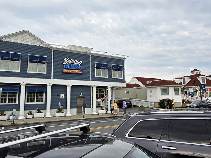 The coastal charm of Bethany Blues' exterior, with its distinctive blue awnings and gray shingles, beckons hungry travelers like a barbecue lighthouse on Delaware's shore.